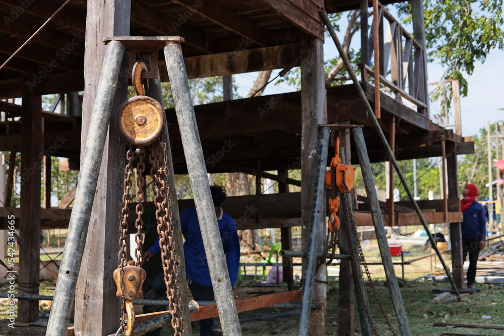 Chain hoist lifting wooden pole. An old chain hoist system on a tripod ...