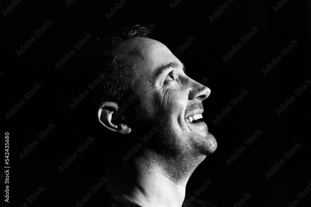 Laughing happy man low key portrait in black and white silhouette in ...