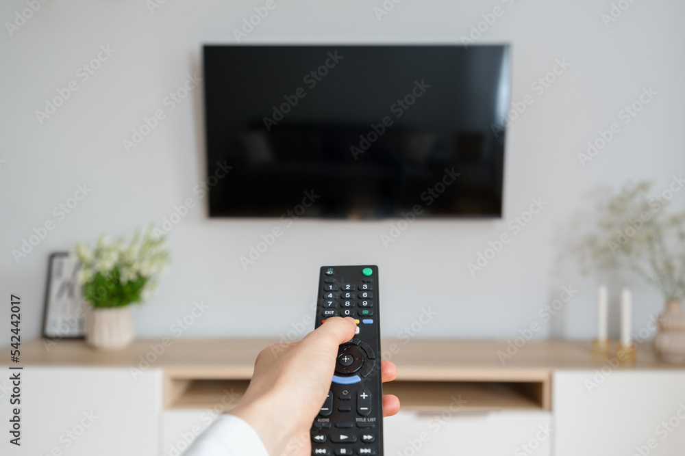 woman watching tv with remote control indoors Stock Photo | Adobe Stock