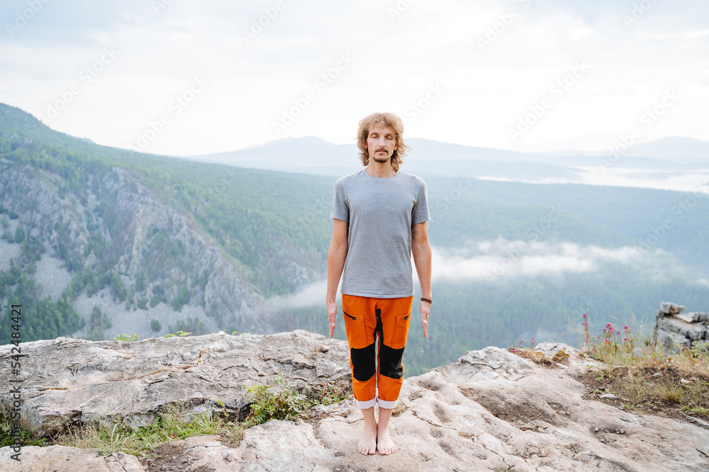 A guy stands in the tadasana pose practices yoga in nature standing in ...
