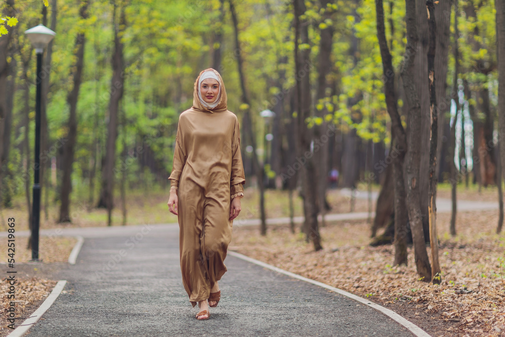 Islamic beautiful woman in a Muslim dress standing on a summer park ...