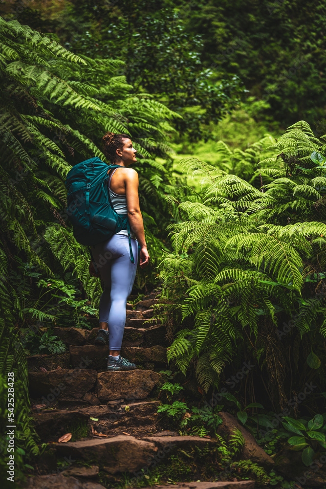 Athletic woman walks up strais on adventurous jungle path with many ...