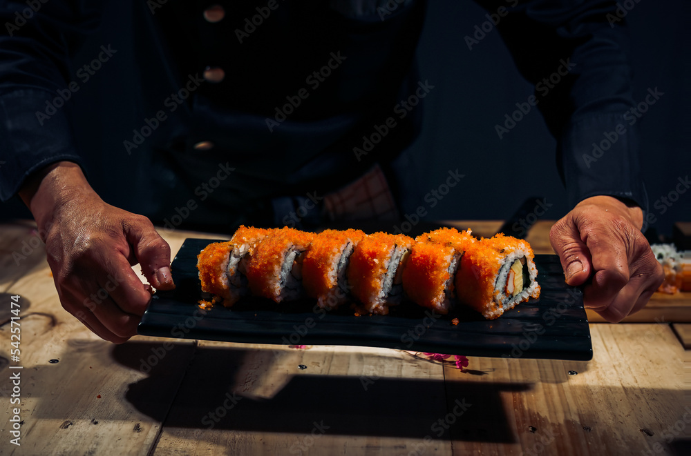 Japanese chef making California Maki Sushi with Masago - Roll made of ...
