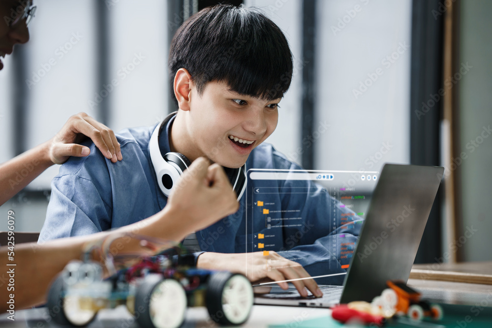 Asian teenager students doing robot arm and robotic cars homework project in house using ...