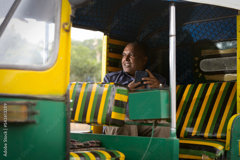 Auto driver using mobile phone while sitting inside auto rickshaw Stock ...