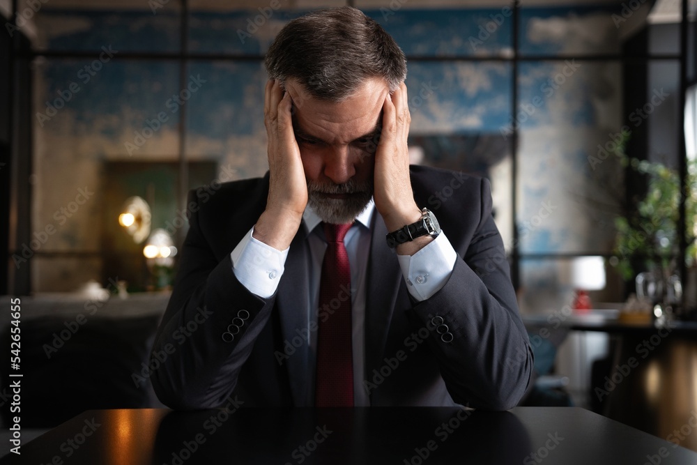 Frustrated mature man sitting in a modern office. Overworked ...