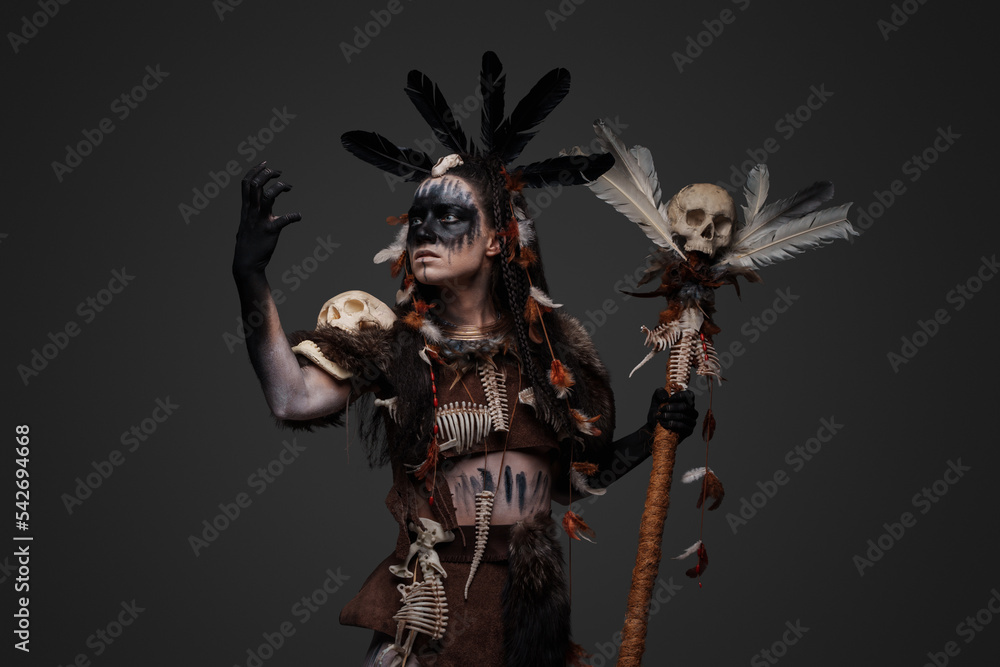 Portrait of spooky voodoo necromancer dressed in dark clothes holding ...