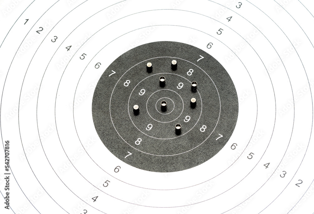 Simple black and white shooting target and metal pellets laying on top ...