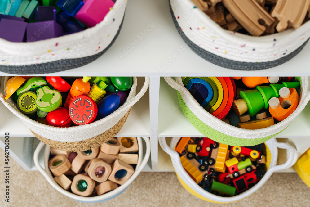Colorful storage baskets on shelves. White shelving with rainbow wooden ...