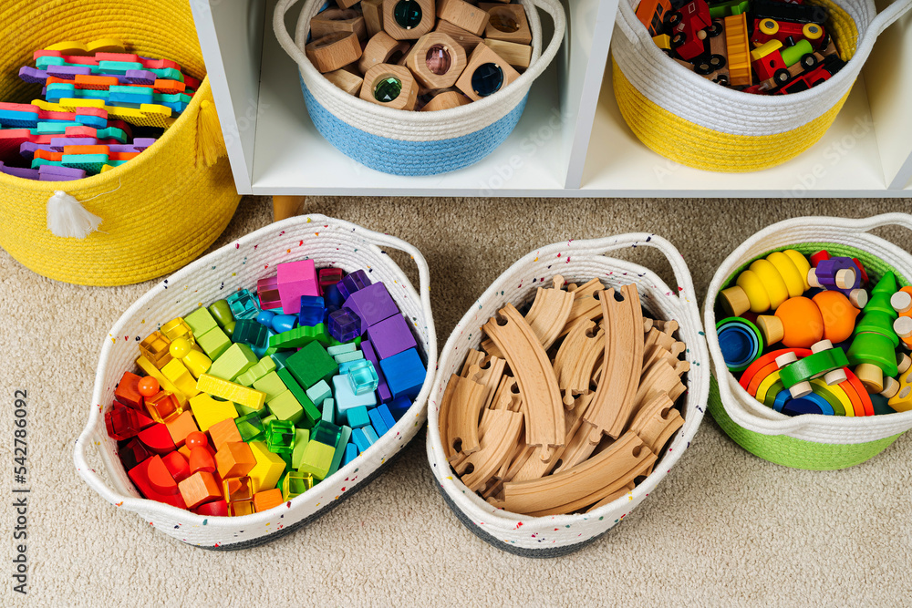 Colorful storage baskets on shelves. White shelving with rainbow wooden ...