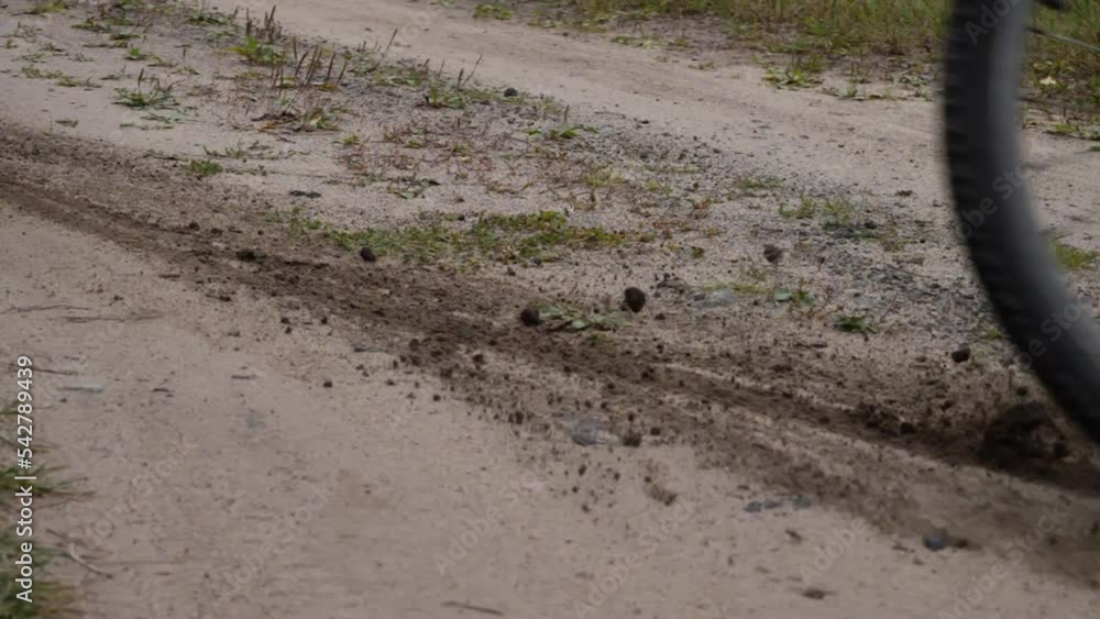 Close-up slow motion footage of a bicycle rear wheel braking on a dirt ...