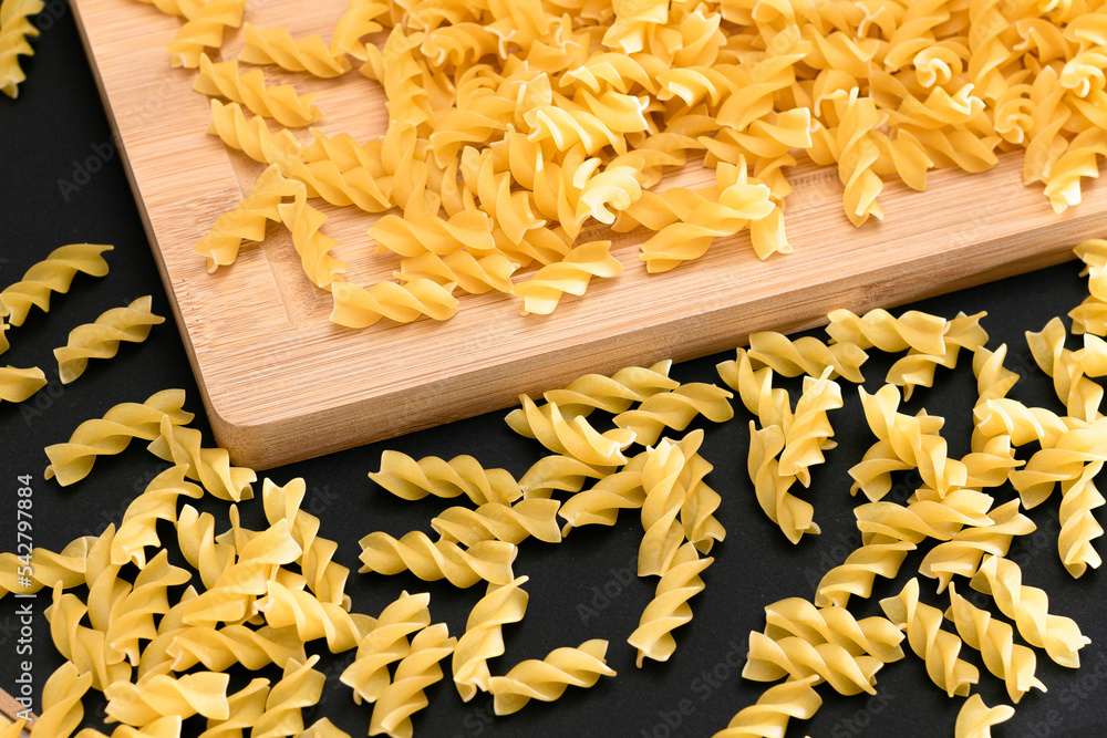 Uncooked Fusilli Pasta Scattered on Wooden Board and Black Table. Raw ...