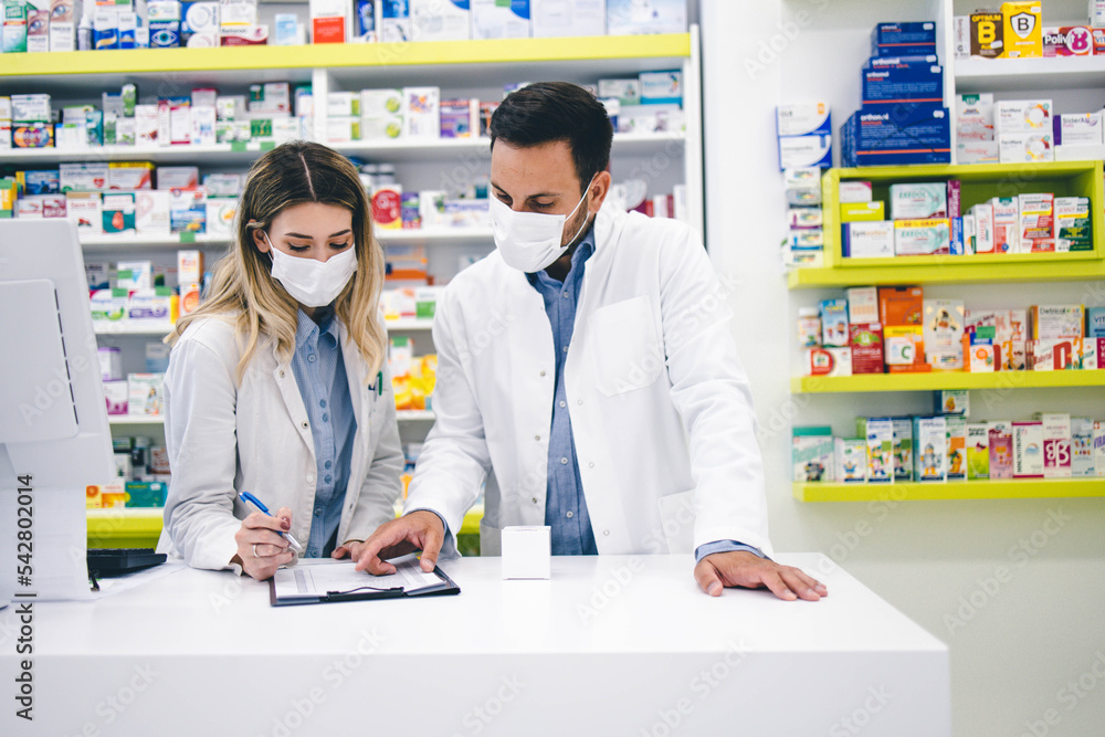 Male and female pharmacy workers on duty, wearing masks and sorting ...