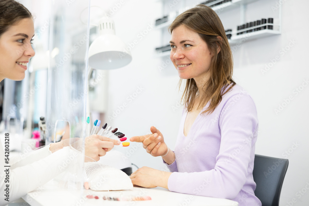 Client girl who came to a nail salon to get a manicure chooses a nail ...