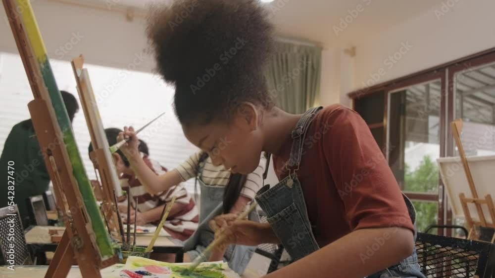 A Black girl concentrates on acrylic color picture painting on canvas ...