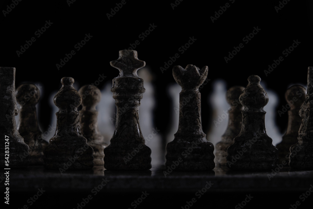 Chessboard set up for battle. Chess pieces in silhouette, low angle ...