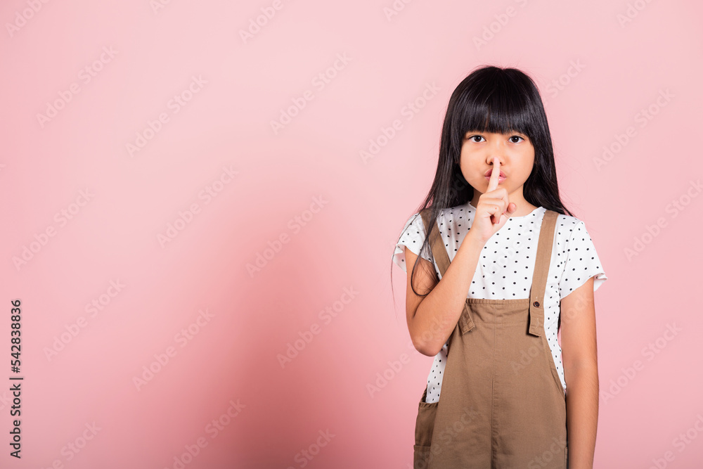 Child secret. Asian kid 10 years old holding finger on lips symbol of ...