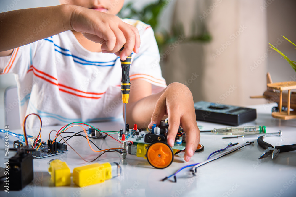 Little child tighten the nut with a screwdriver to assemble car toy ...