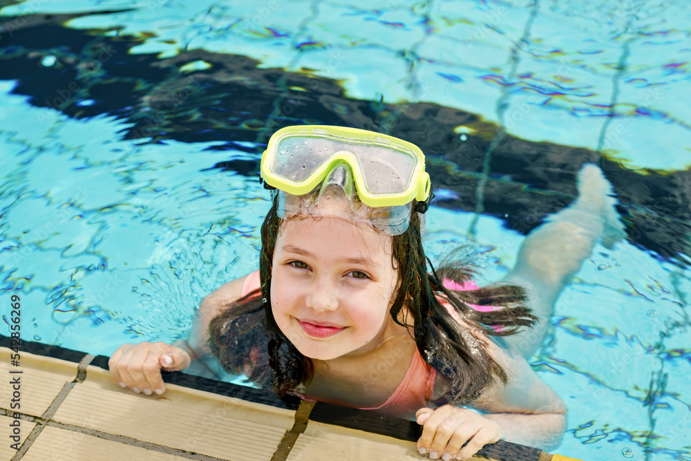 Cute happy young girl in goggles swimming and snorking in the swimming ...