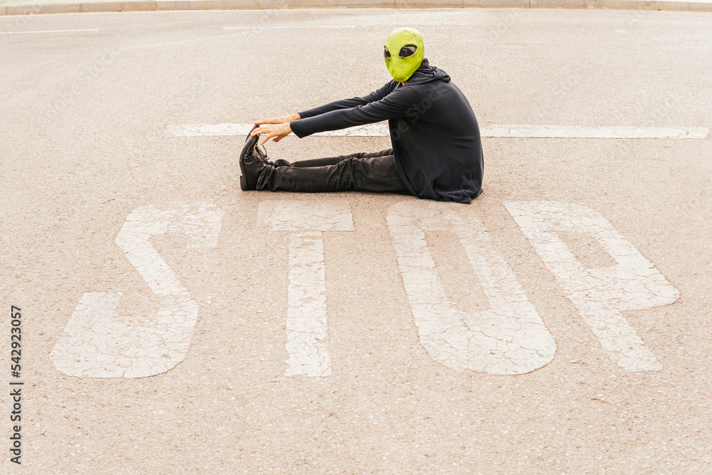 Man wearing alien mask sitting in front of STOP sign on road Stock ...