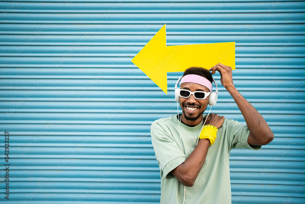 Happy man holding arrow sign on head standing in front of closed blue ...