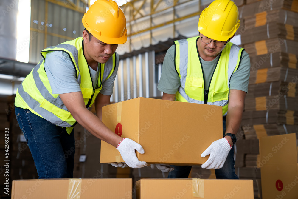 Warehouse workers work in teams and lift sealed cardboard boxes for ...