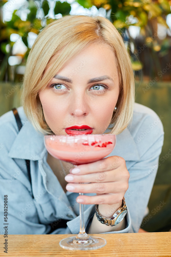 Portrait of attractive young woman drinking coctail in cafe indoor ...