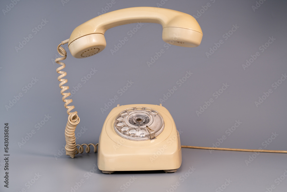 Old beige aged rotary telephone with removed hanging receiver on grey ...