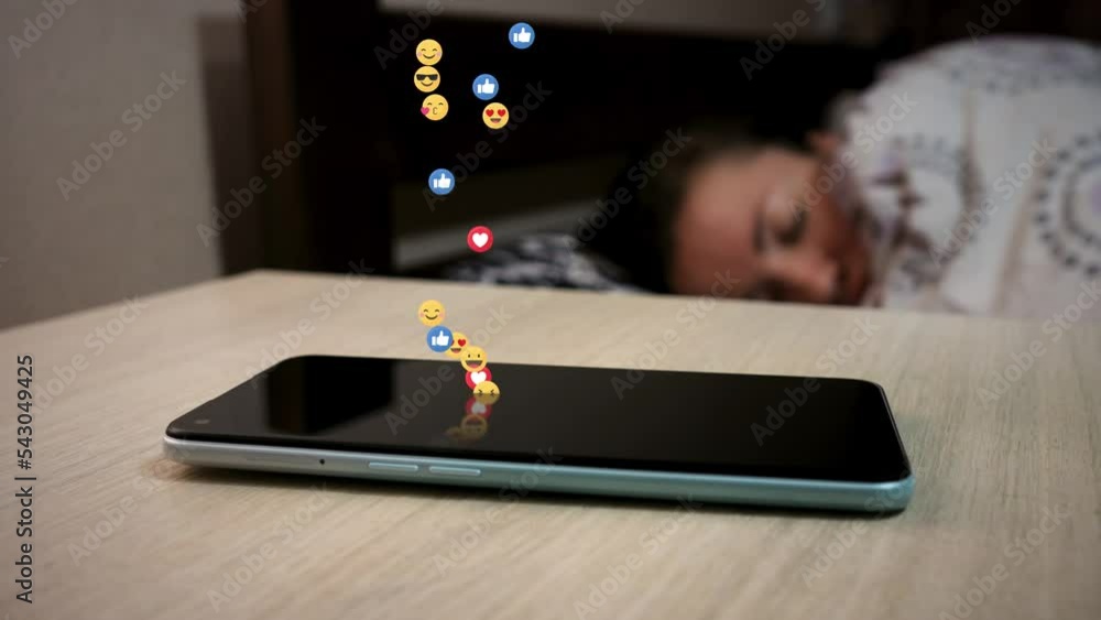 Positive emoji appears on mobile smartphone, which lies on the bedside ...