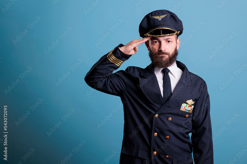 Serious airplane pilot saluting, wearing uniform and hat front view ...
