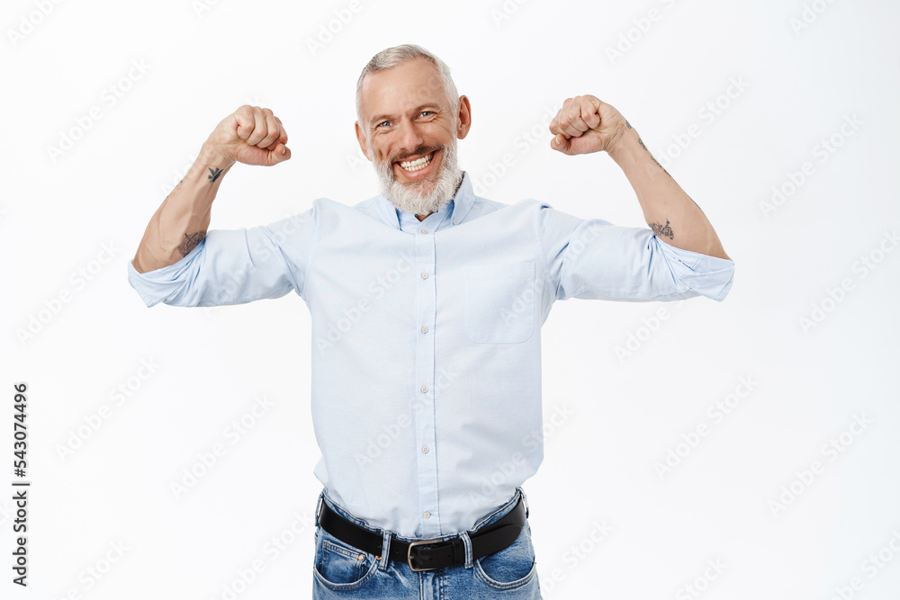 Stong and confident mature man with grey hair, smiling and flexing ...