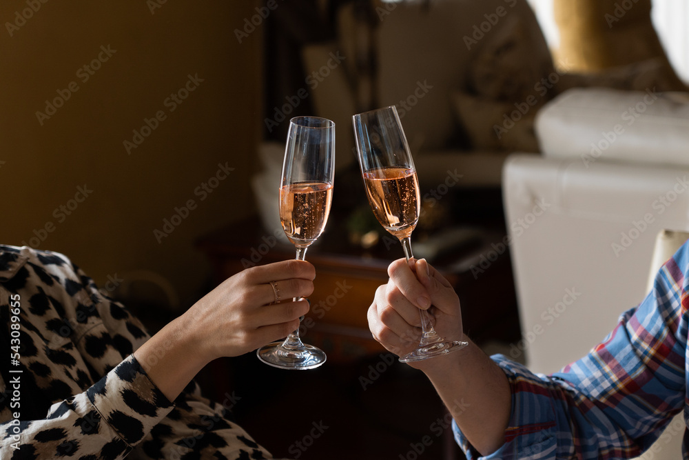 Two people toasting with pink champagne glasses with no faces. Two arms ...