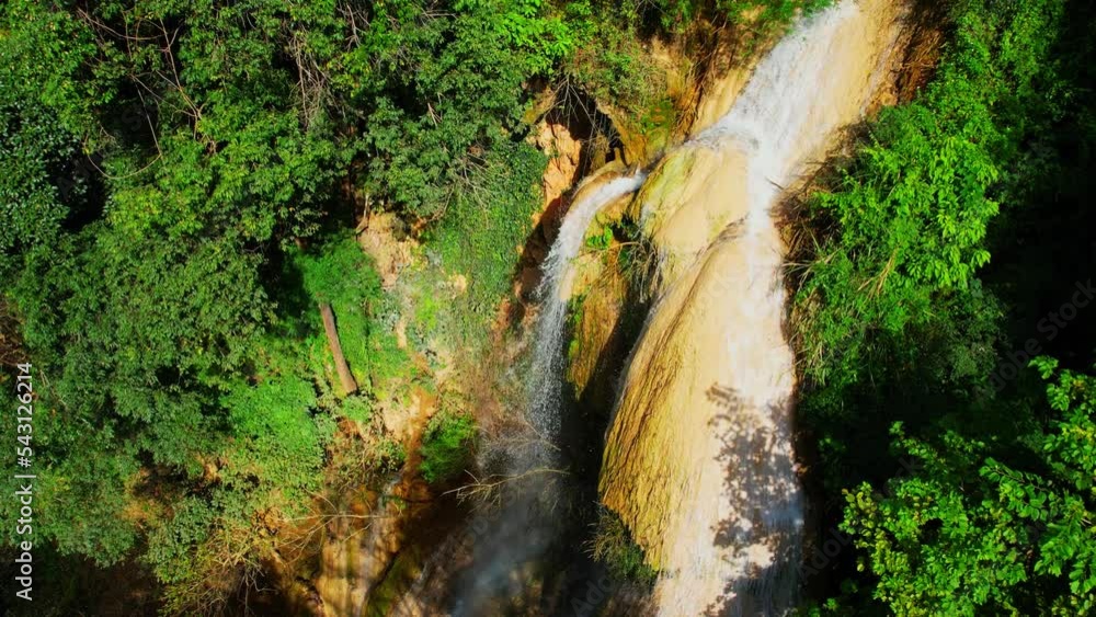 Drones fly over Tad Mok Waterfall during sunlight, Water flows over the ...