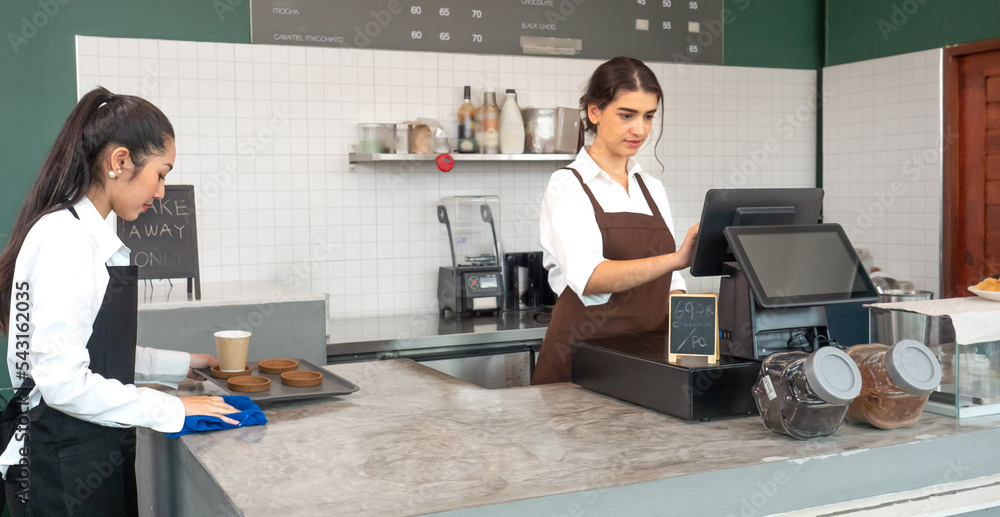 Foto de Beautiful female cashier standing at counter working with cash ...