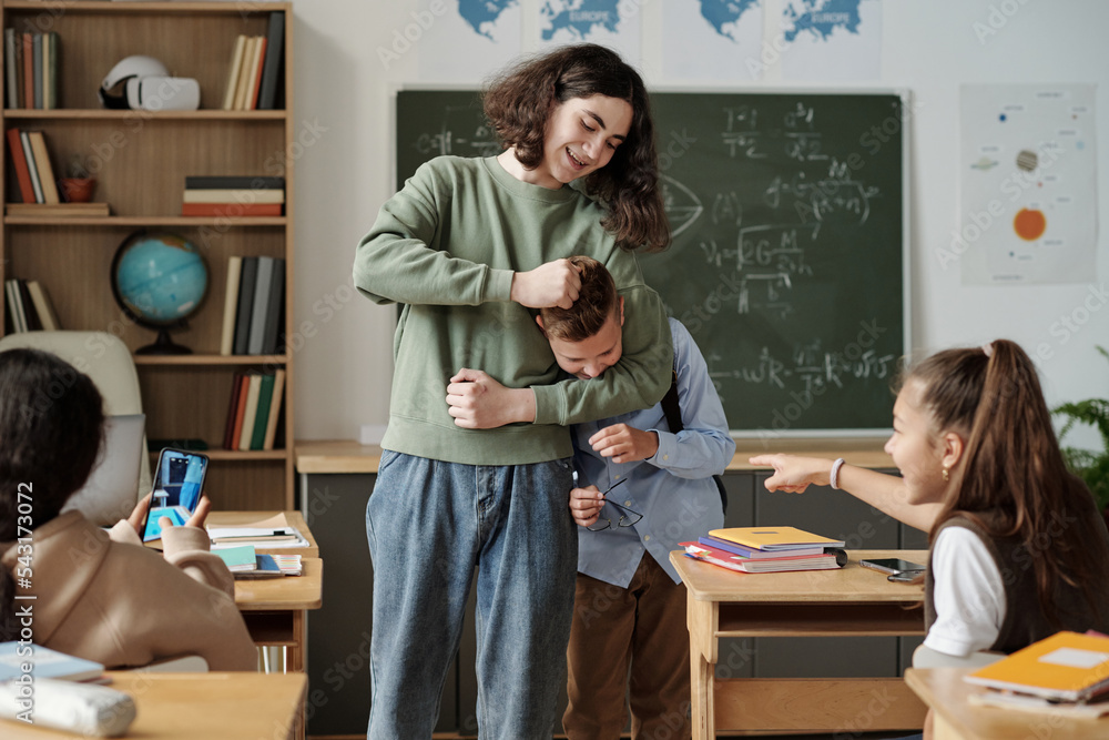 Two girls laughing at junior school learner while one of them making ...