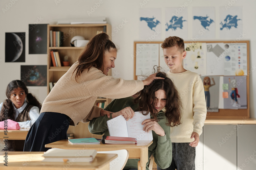 Cruel schoolgirl laughing at classmate and pulling his hair while ...