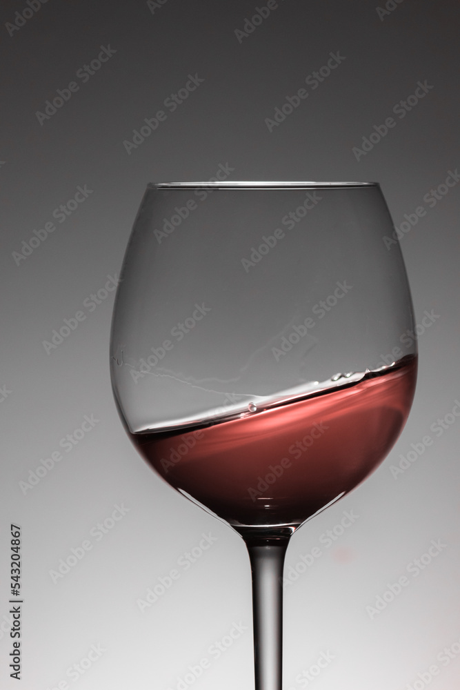 Vertical close up view of a tilted red wine cup. Stock Photo | Adobe Stock