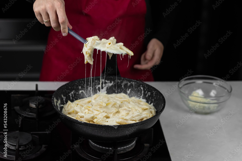 Chef cook making mac and cheese with white cream sauce. Pasta macaroni ...