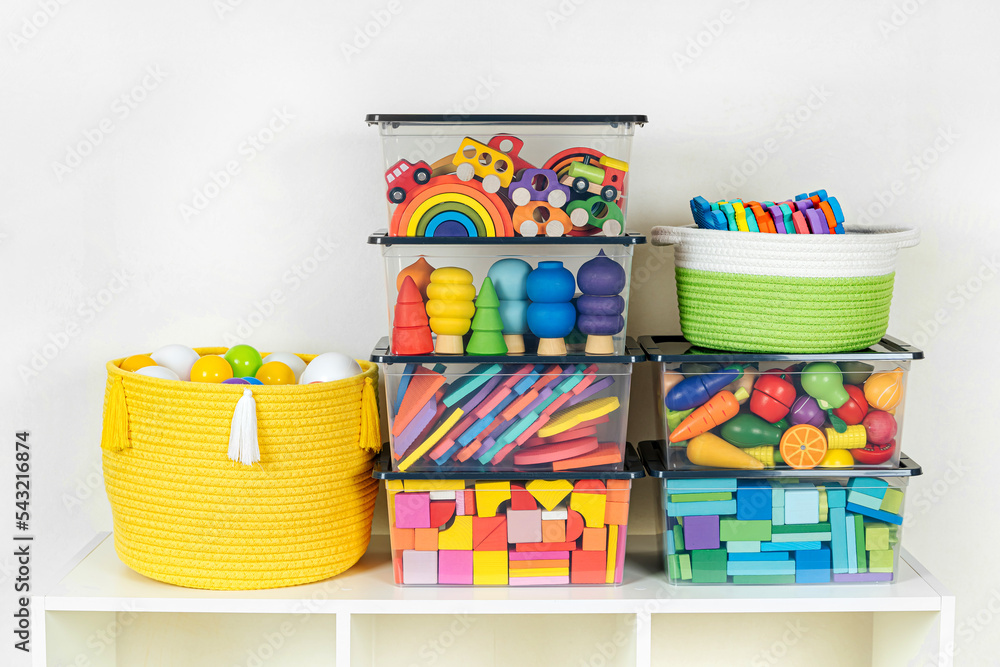 Transparent plastic containers with various children's toys on shelves ...