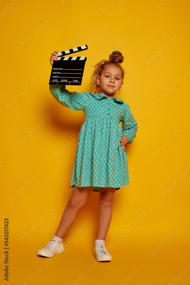 Lovely smiling little girl holding director's film movie slateboard ...