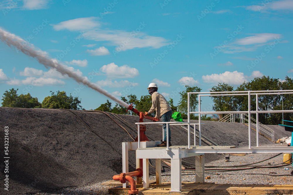 Male water firefighter in training fight tank oil fire from the pipe ...