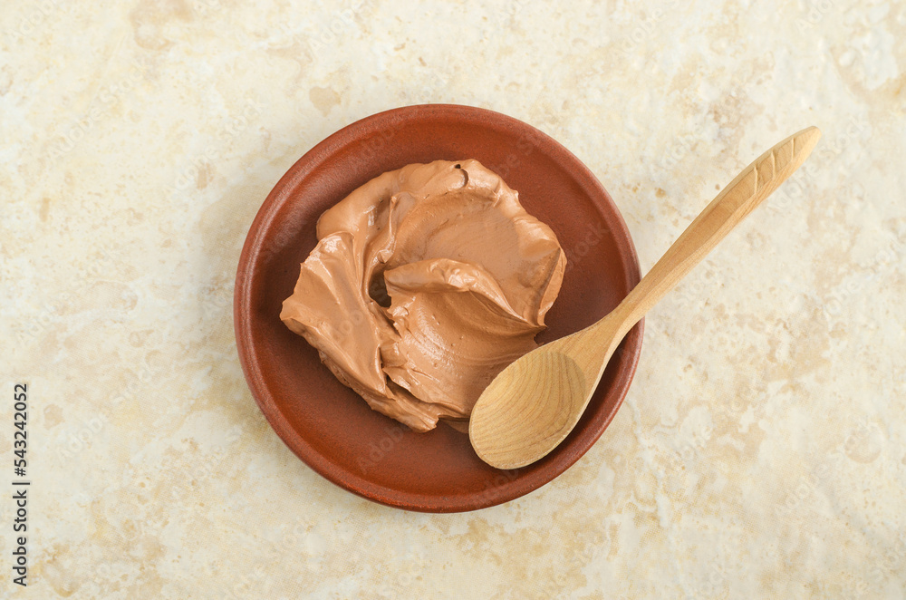 Red moroccan bentonite clay on a small clay plate and wooden spoon. Diy ...