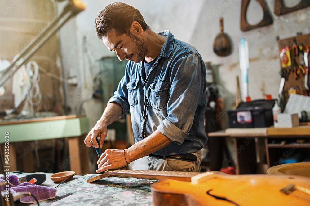 A luthier adjusts the truss rod of a semi-acoustic guitar in his ...