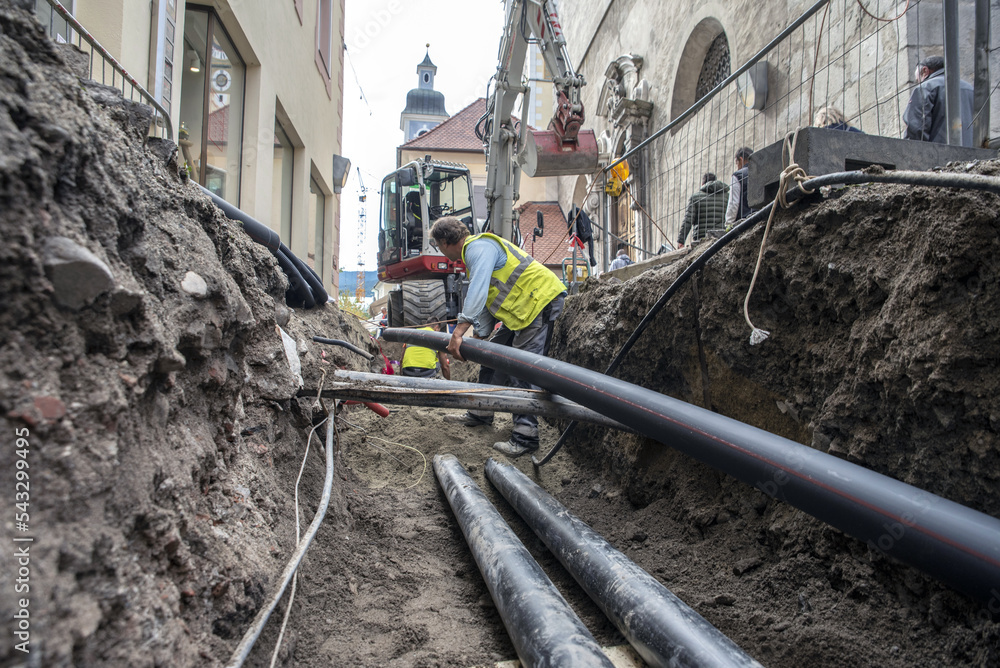 Workers install underground pipes for water, sewerage, electricity and ...