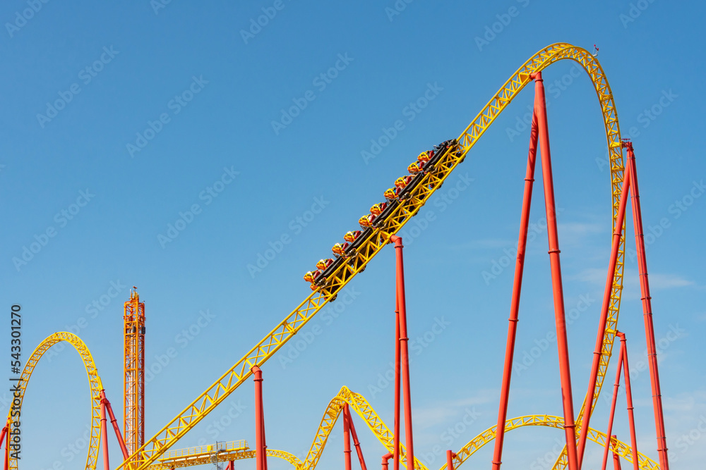 Yellow and red roller coaster with upturning trolleys on a turn and a ...