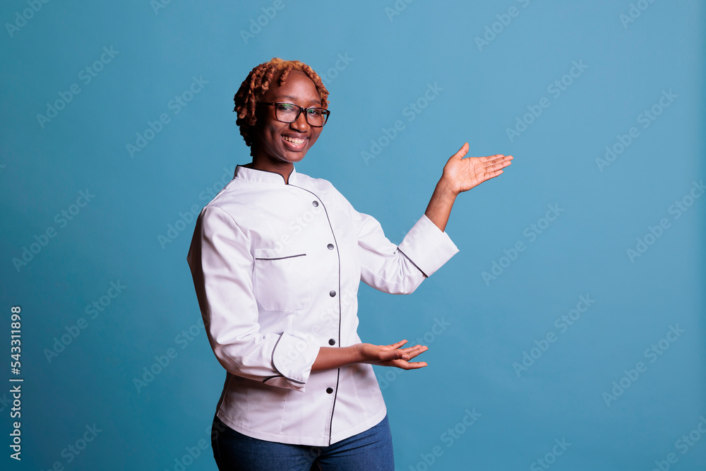 Smiling professional cook in kitchen uniform holding imaginary product ...
