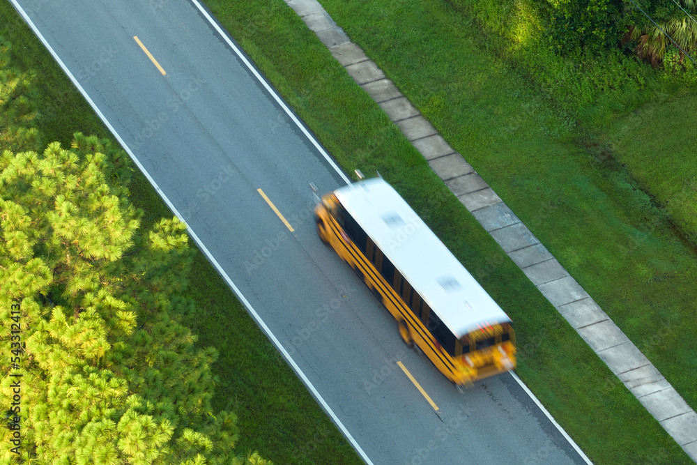 Aerial view of american yellow school bus driving on suburban street ...