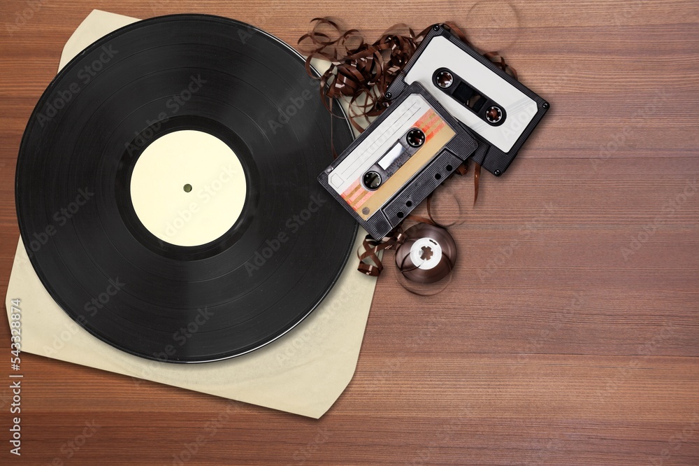 Vinyl records, cassette tapes and cassette recorder on table. Retro ...