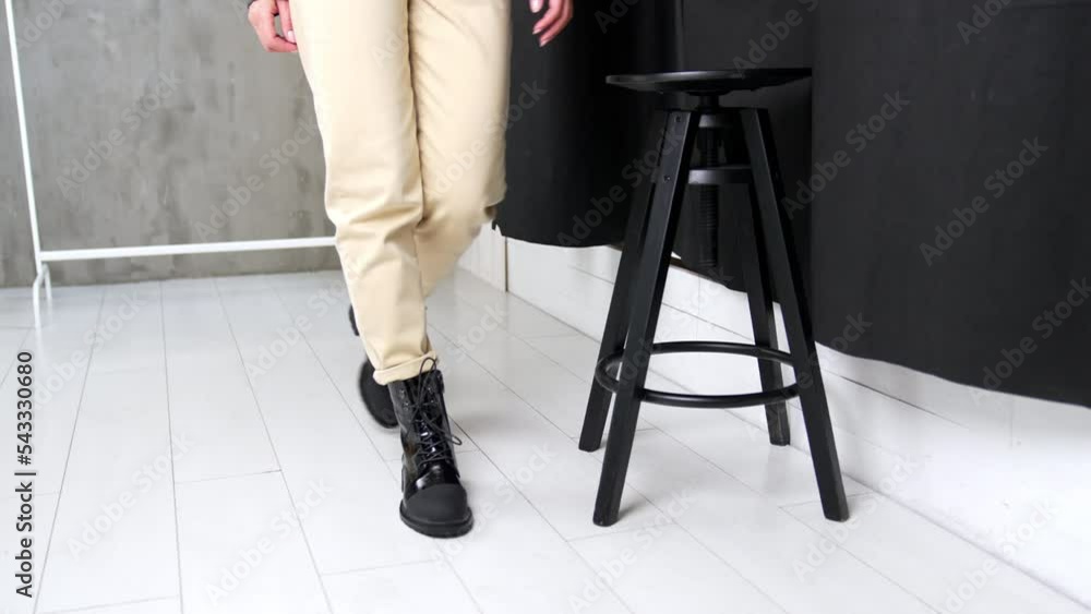 Unknown woman comes up to a high stool and sits down. Model ...