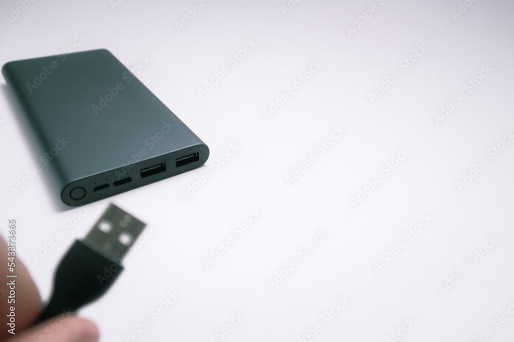 Hand holding USB cable and grey power bank. Hand connecting USB cable ...